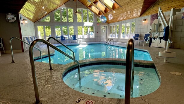 Piscina interior com indicador de profundidade de 90 centímetros, cercada por espreguiçadeiras e teto de madeira.