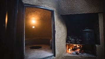 Um interior rústico com lareira, porta de madeira e parede de pedra.