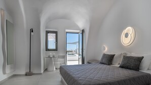 Quarto moderno com uma cama grande, uma pequena escrivaninha e vista para o exterior.