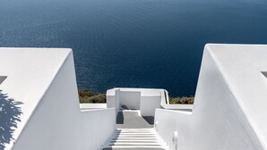 Uma escadaria branca leva a uma varanda com vista para o mar.