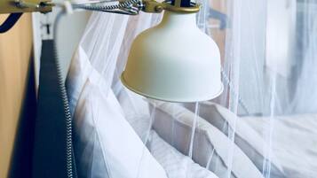 Cama com dossel branco e luminária suspensa.