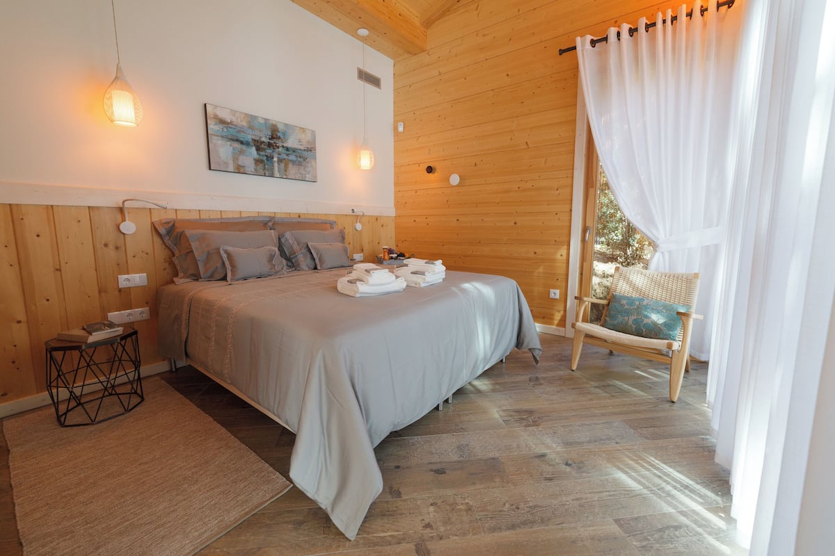 Quarto com cama, cadeira, pintura e teto de madeira.
