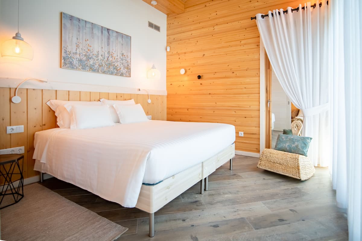 Quarto com cama, mesa de cabeceira, abajur e obra de arte na parede.