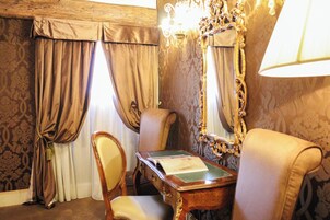 Quarto com teto de madeira, uma escrivaninha com cadeira, espelho e cortinas.