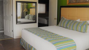 Quarto de hotel com uma cama grande, um espelho, um quadro na parede e uma porta para outro cômodo.