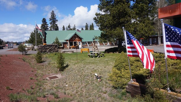 Uma cabana com telhado verde, parede de pedra e uma bandeira americana.