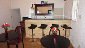 Uma cozinha moderna com área de bar, banquetas de madeira e uma mesa de jantar com cadeiras.
