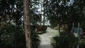Um caminho de pedra serpenteia por um jardim com diversas plantas e árvores.