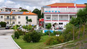 Um hotel com telhado de telhas vermelhas, piscina e vegetação exuberante.