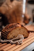 Uma barra de pão sobre uma tábua de cortar de madeira, com um pano por baixo.