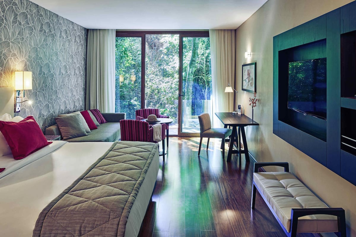 Quarto de hotel com uma cama, um sofá, uma mesa de jantar e uma televisão.