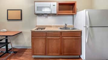 Cozinha compacta com micro-ondas, pia e geladeira.