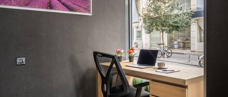 Escritório moderno com mesa, cadeira e vista para a rua, onde se veem bicicletas e uma árvore.