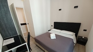 Um quarto com uma cama, uma escrivaninha e uma cadeira.