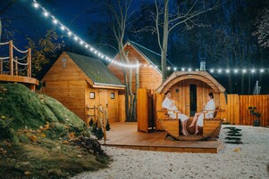 Uma cabana de madeira com sauna, rodeada por um deck e luzes de corda.