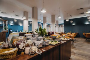 Espaço de buffet com diversas opções de comida e área de estar com cadeiras.