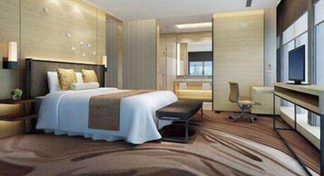 Quarto de hotel moderno com uma cama grande, uma escrivaninha e uma televisão.