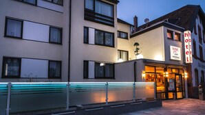 Um hotel com fachada moderna, entrada visível e uma placa indicando sua localização em Heidelberg.