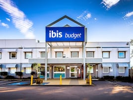 Um edifício moderno com uma placa que diz 'ibis budget'.