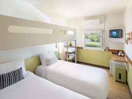 Quarto de hotel com duas camas, televisão, janela com vista, pia e uma pequena cozinha.