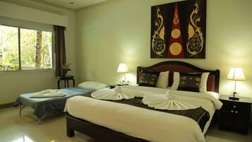 Quarto de hotel com uma cama grande, uma cama menor, duas mesas de cabeceira com luminárias, uma janela com cortinas e uma parede com um quadro decorativo.