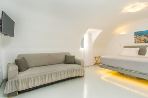 Quarto moderno e minimalista com sofá e cama, paredes brancas e um quadro na parede.