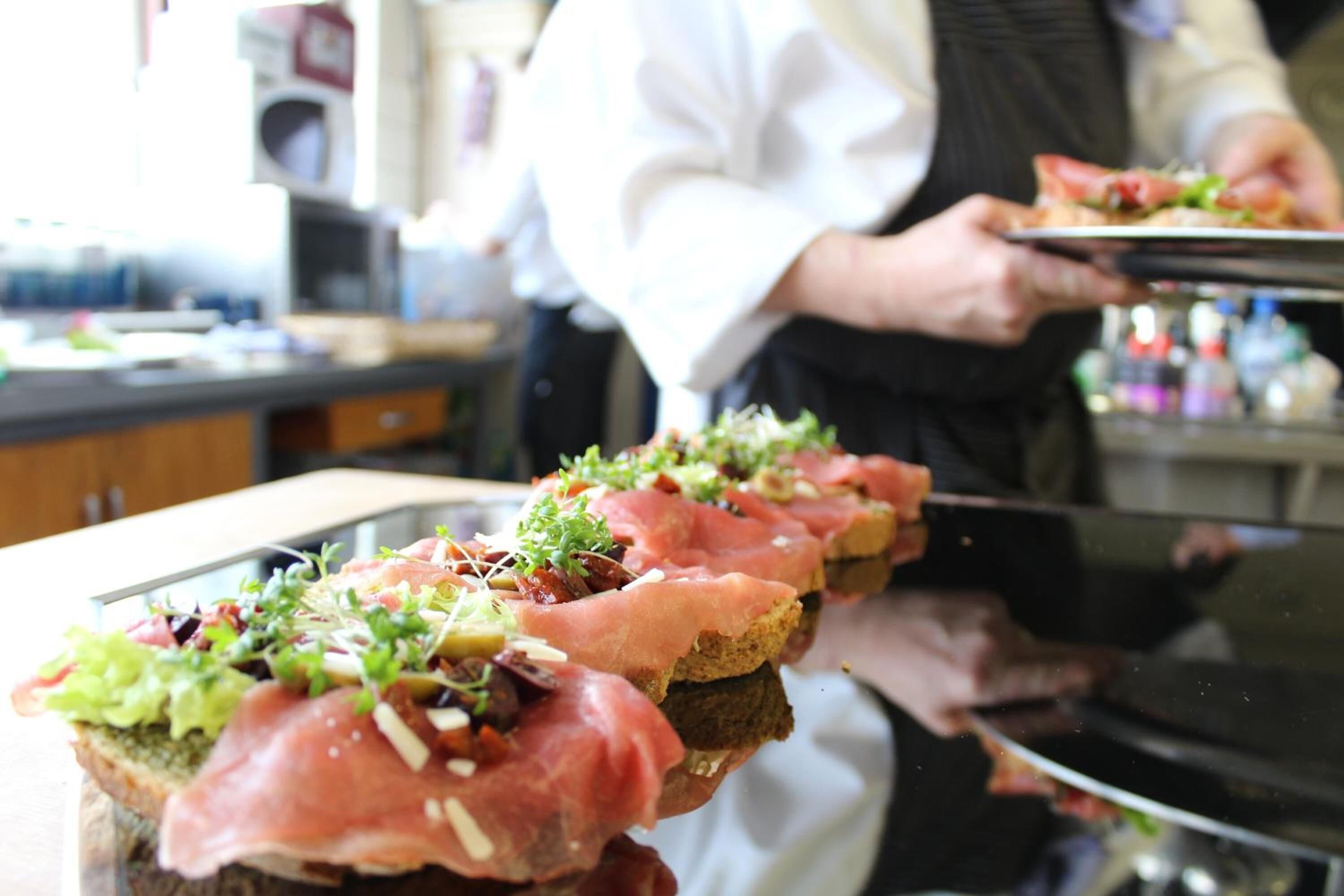 Um chef preparando um prato com pão, verduras e carne.