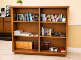 Uma estante de madeira com várias prateleiras contendo livros, revistas e fichários.