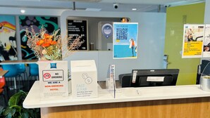 Balcão de recepção de hotel com placa de proibido fumar, código QR para check-in digital e aviso indicando que o hotel é para não fumantes.