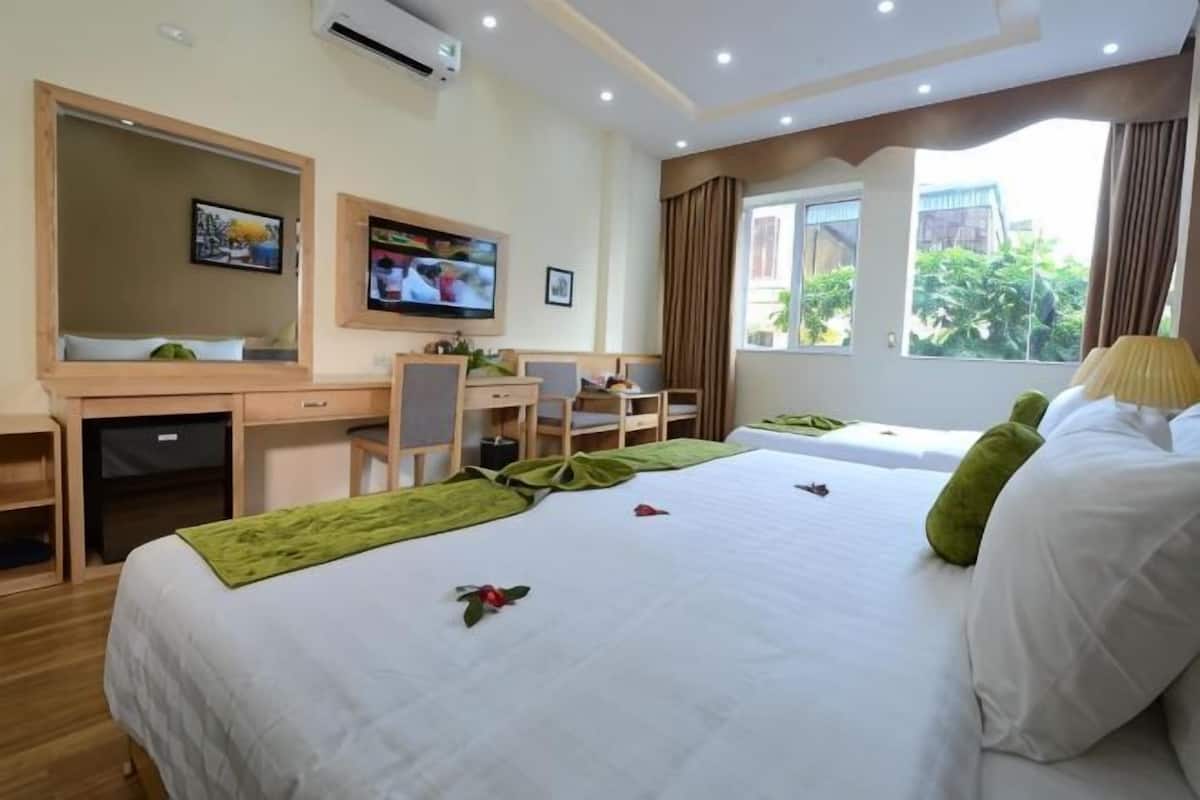 Quarto de hotel com cama, escrivaninha, cadeira, televisão e janela com vista.