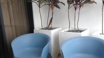 Um quarto com uma cadeira azul, uma mesa branca e uma planta.