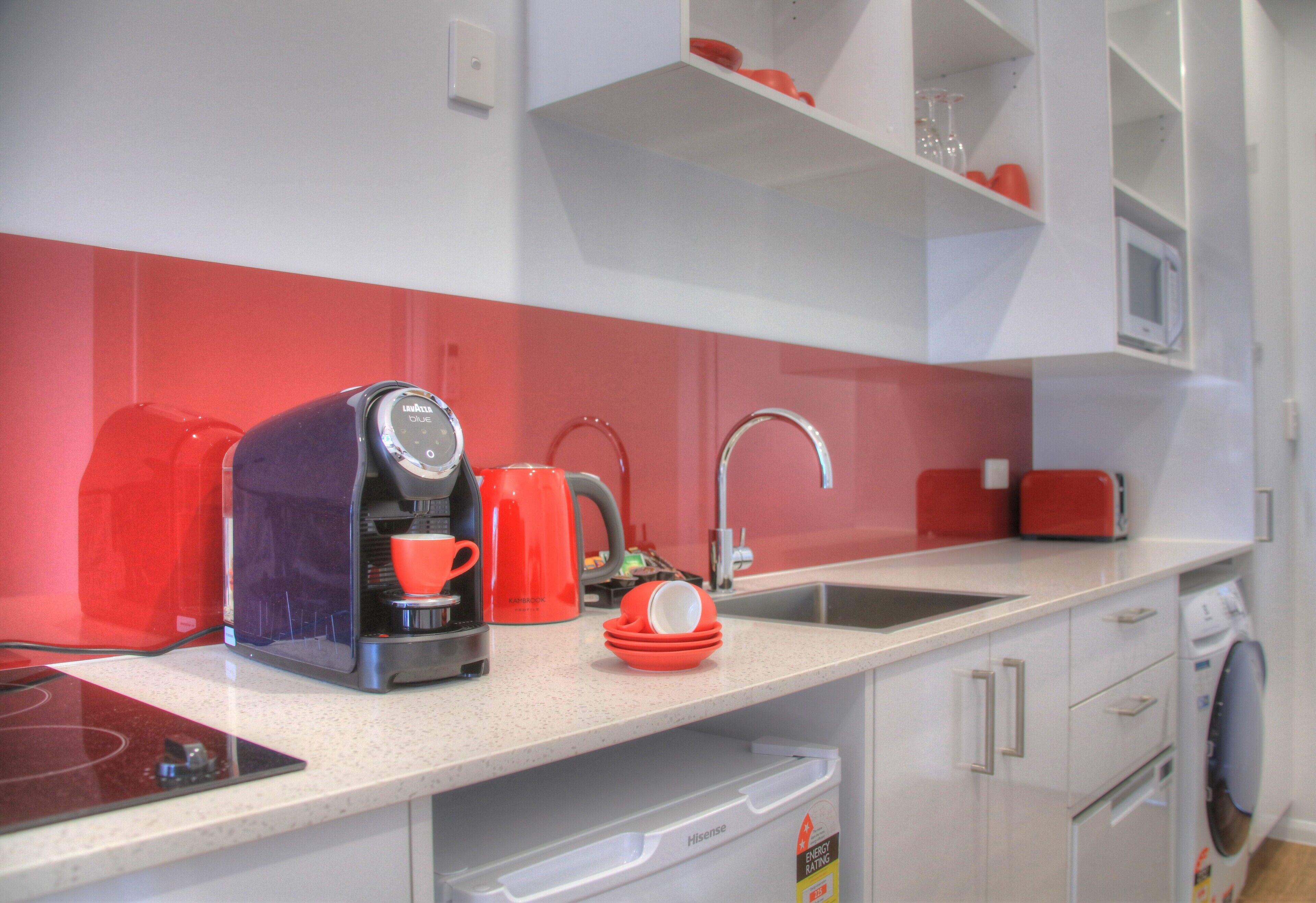 Cozinha moderna com cafeteira, pia e micro-ondas.