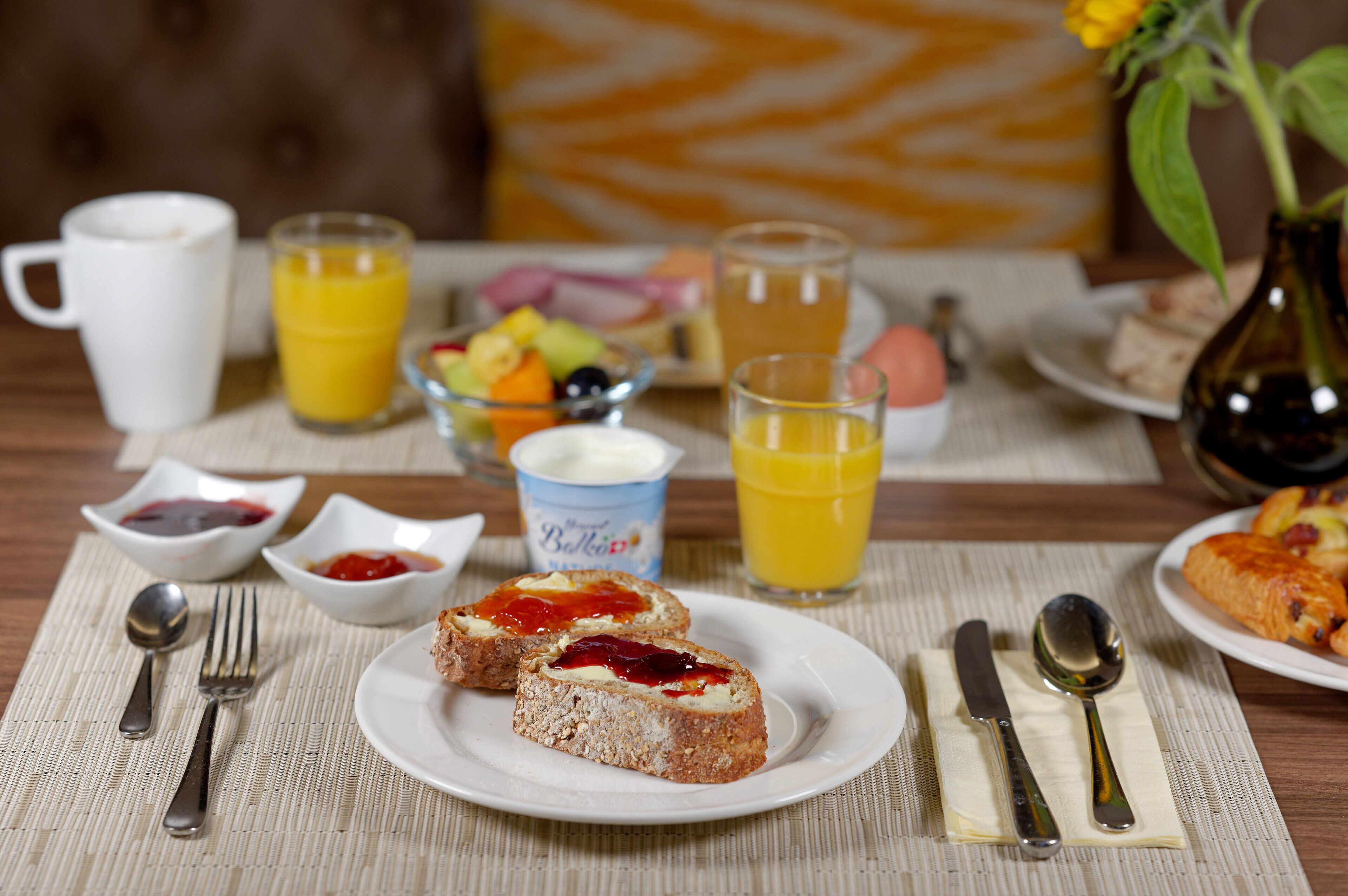 Uma mesa posta para o café da manhã, com torradas, frutas e bebidas.