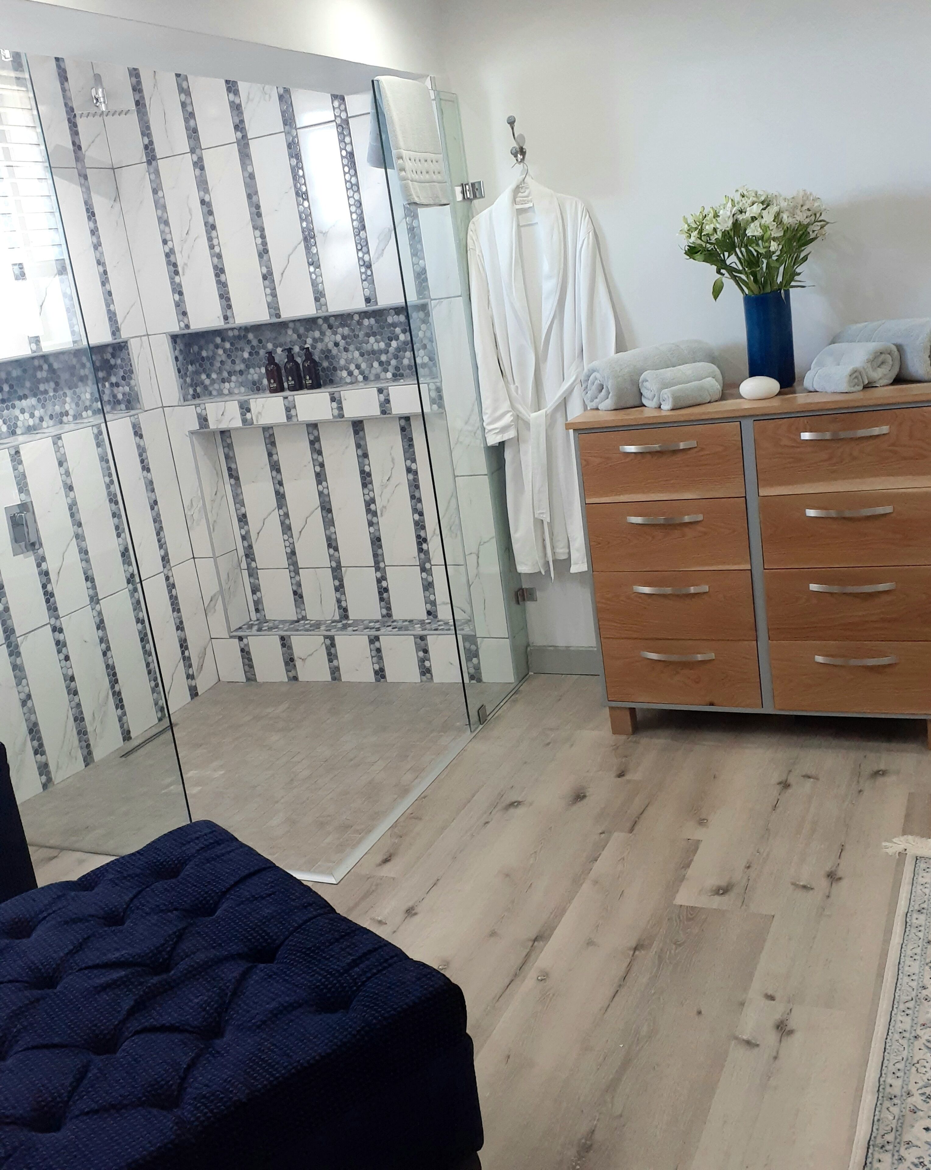Casa de banho com chuveiro, espelho e toucador com um porta-toalhas.