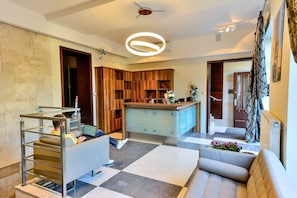 Um hall de hotel moderno com uma mesa de recepção, área de estar e uma escadaria.