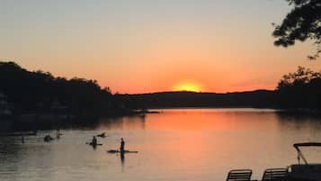 Um pôr do sol sobre um lago calmo, com barcos e um cais.