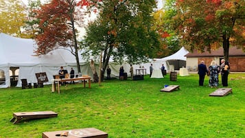 Um evento ao ar livre com tendas e mesas montadas em um gramado.