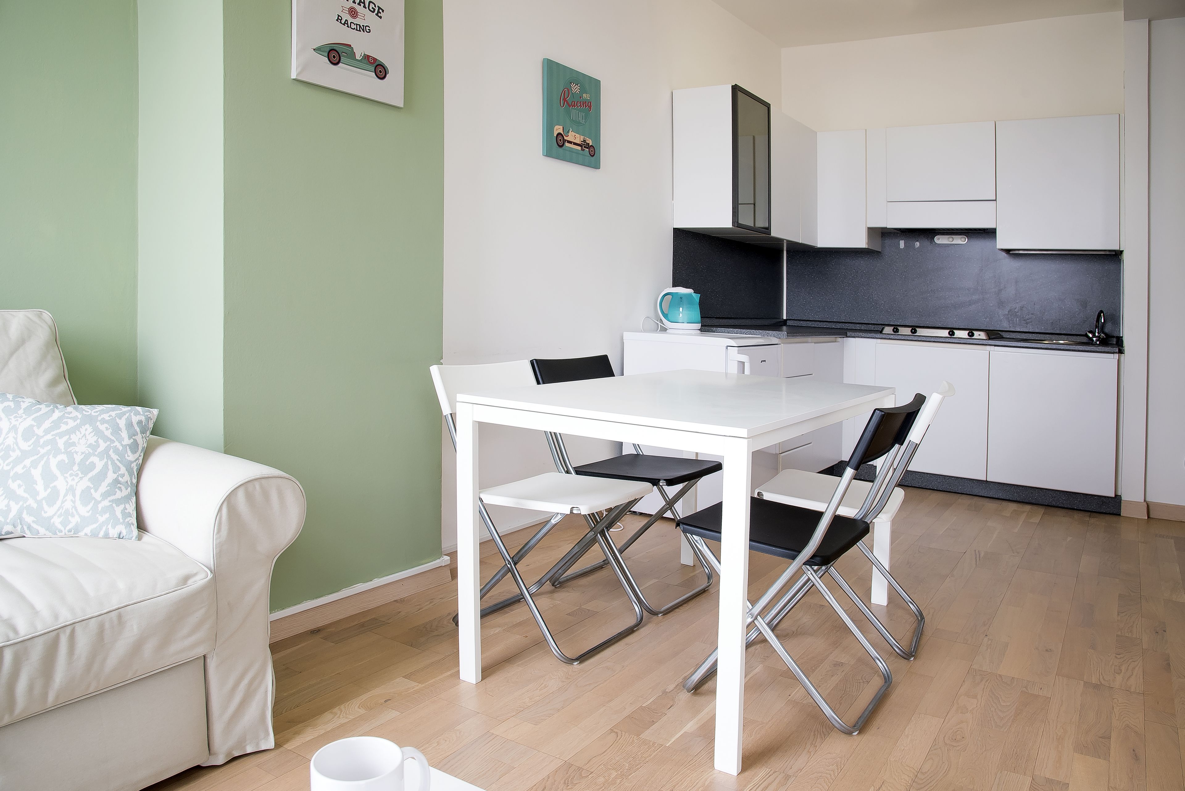 Um espaço compacto com cozinha compacta, mesa de jantar com cadeiras, sofá e mesa de centro.