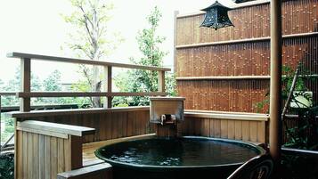 Uma área de hidromassagem com deck de madeira, cerca de bambu e um lanterna pendurada.