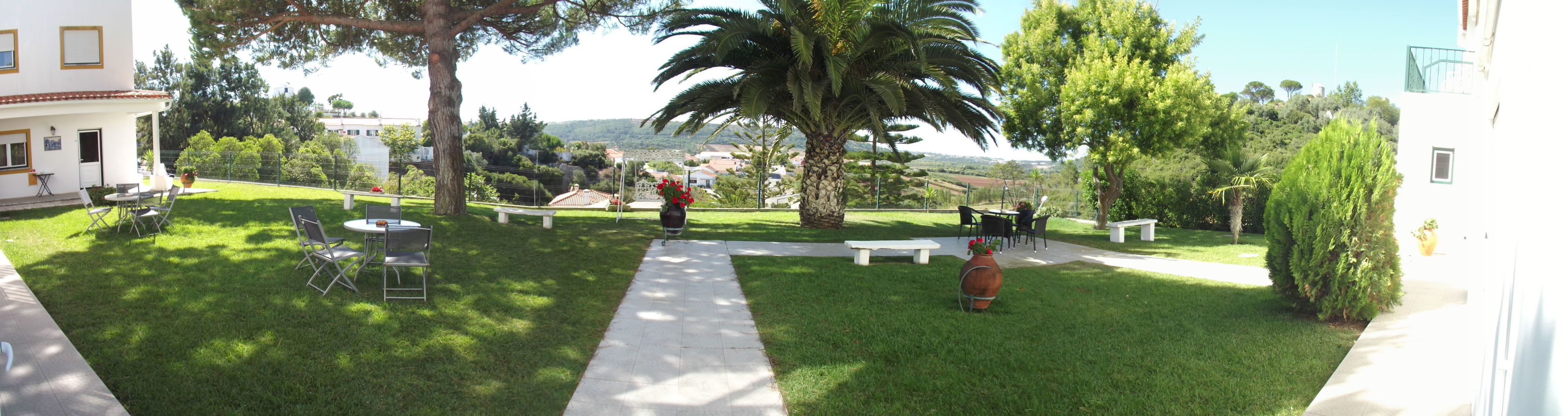 Um pátio com gramado, mobiliário para área externa e vista da paisagem ao redor.