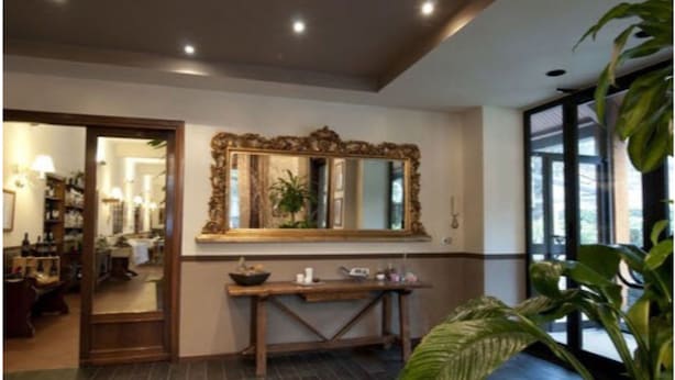 Um interior moderno com um espelho grande e ornamentado, uma mesa consola de madeira e uma planta em vaso.