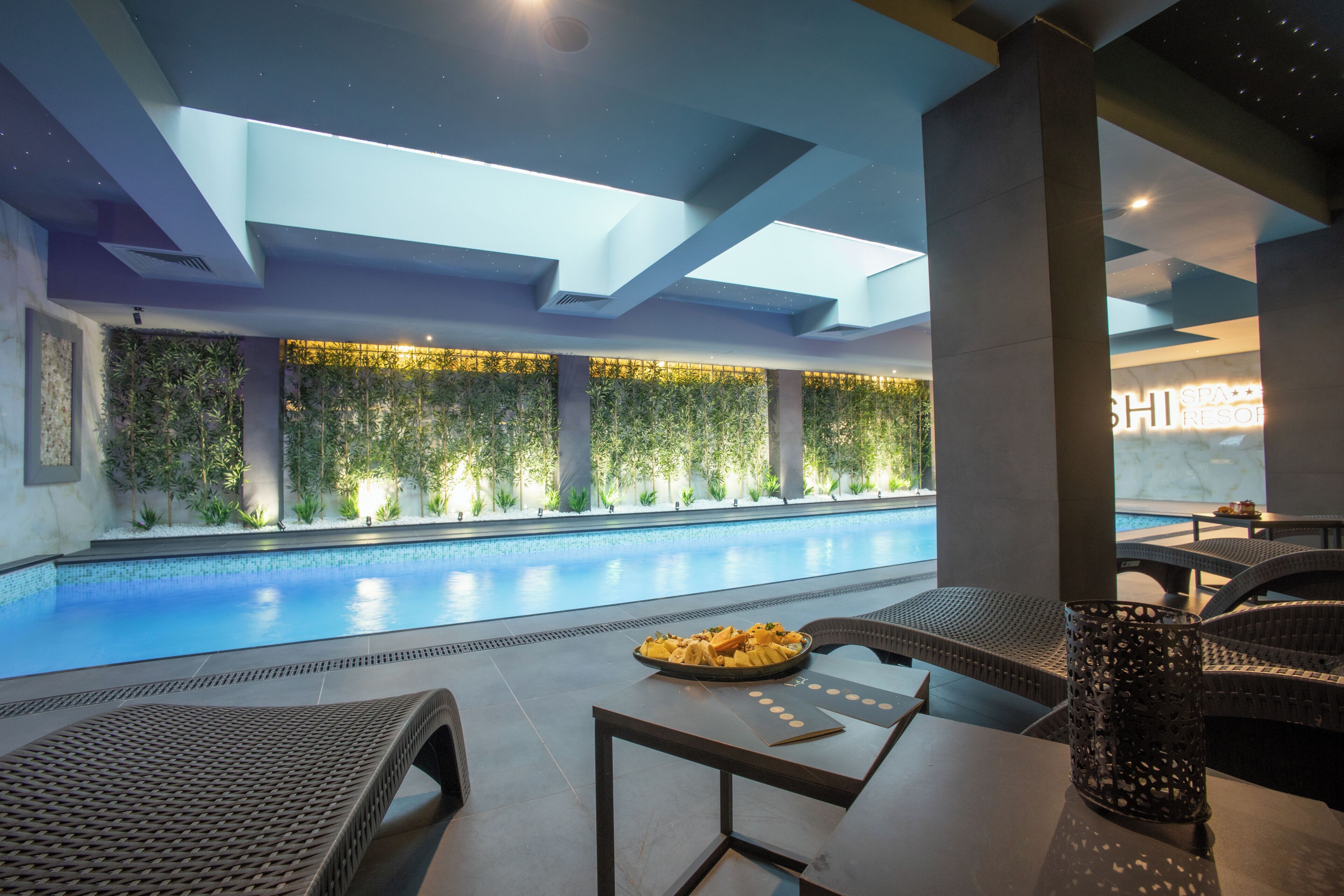 Área ao lado da piscina com mesa, cadeiras e um vaso decorativo.