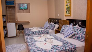 Quarto de hotel com duas camas, televisão, escrivaninha e guarda-roupa.