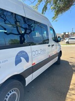 Uma van branca com o logotipo Dolphin e texto indicando sua associação com Noronha - Vila Hotel.