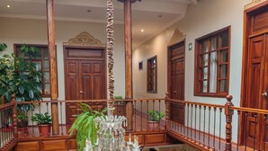 Um interior com vários níveis, varandas de madeira, um candelabro central e plantas em vasos.