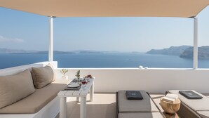 Uma área de estar moderna ao ar livre, com uma mesa posta para dois, com vista para uma paisagem deslumbrante do mar e ilhas ao longe.