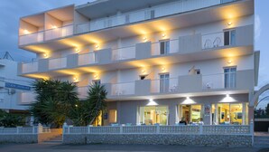 Hotel com vários andares, varandas, uma parede de pedra e um restaurante no andar térreo.