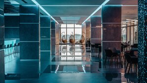 Um lobby moderno com piso refletivo, área de estar e vista para o mar.