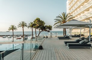 Um deck com cadeiras de descanso e piscina com vista para o mar.