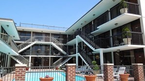 Um hotel de vários andares com um pátio central, piscina ao ar livre e várias varandas.